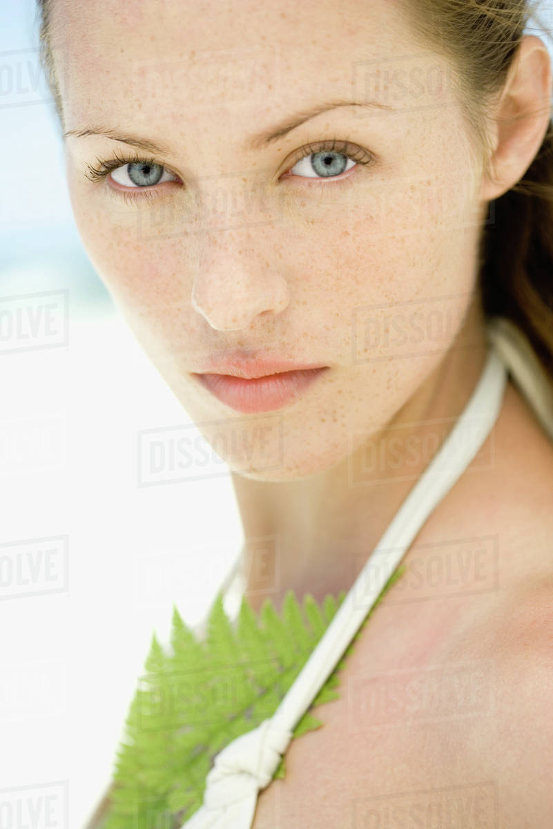 Woman wearing halter top bathing suit, leaf against chest, looking at ...