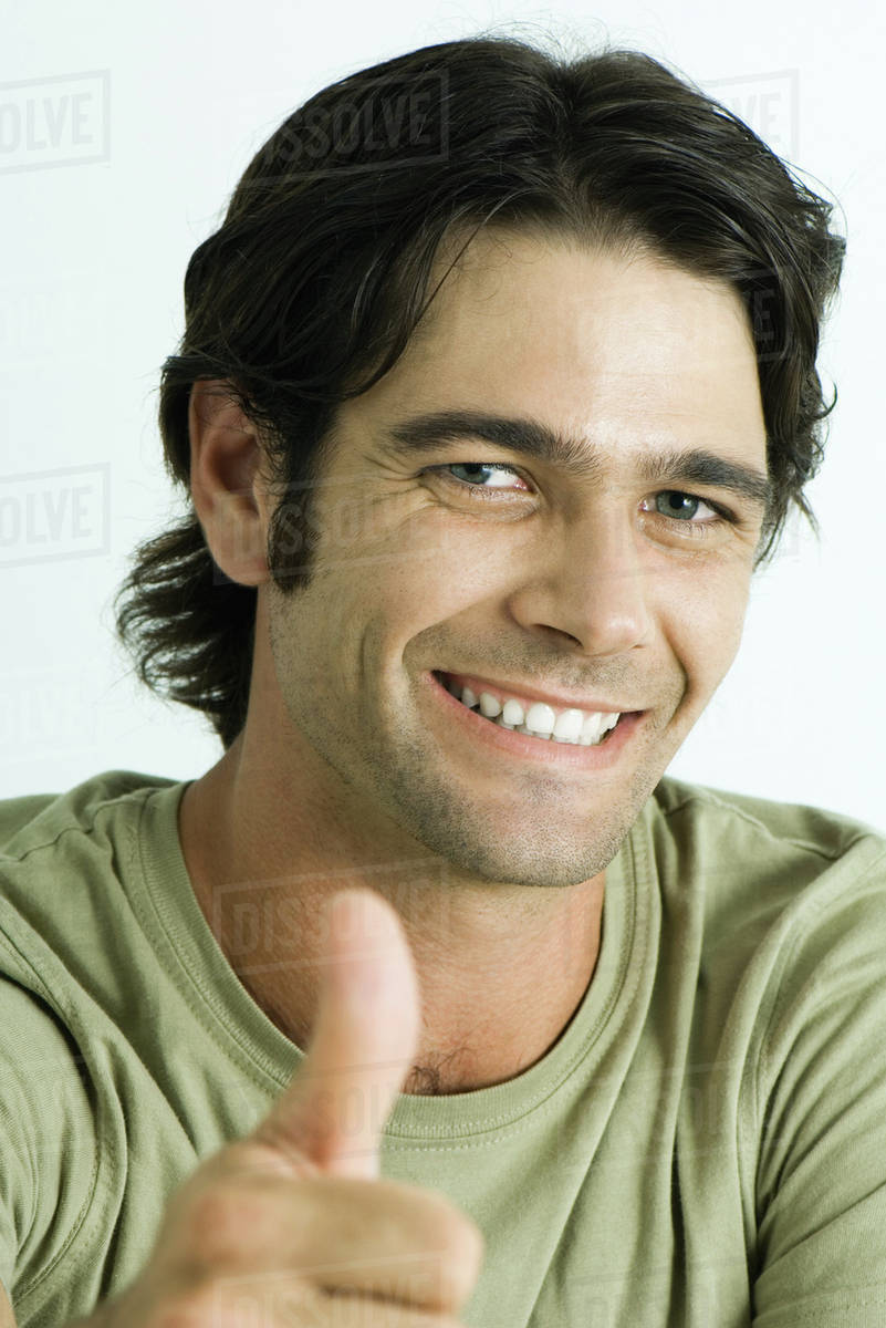 Man smiling at camera, giving thumbs up signal, head and shoulders ...