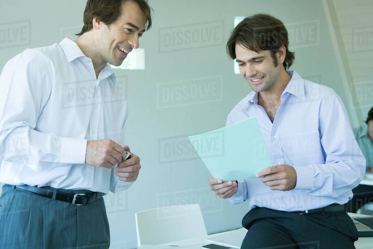 Two businessmen looking at document, smiling - Stock Photo - Dissolve