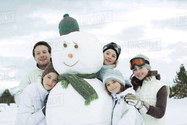 Group of young friends gathered around snowman - Royalty-free Stock ...
