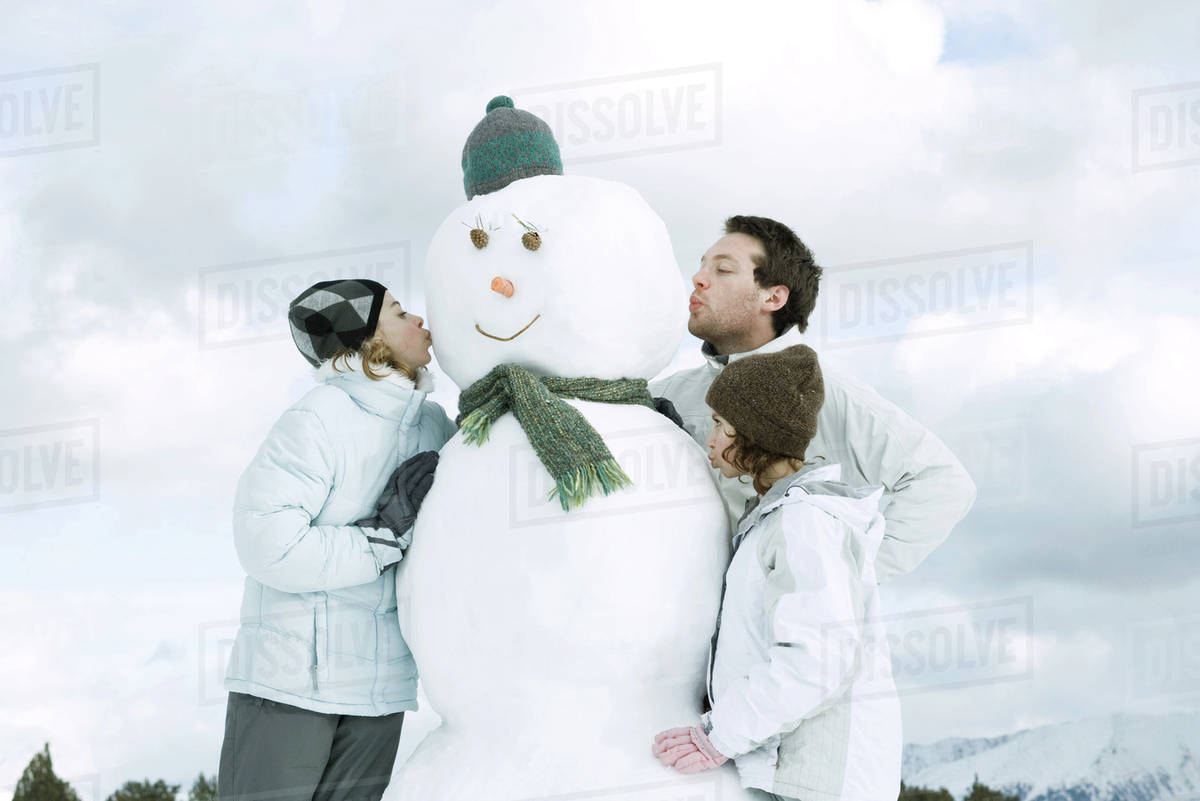 Three young friends kissing snowman - Royalty-free Stock Photo | Dissolve