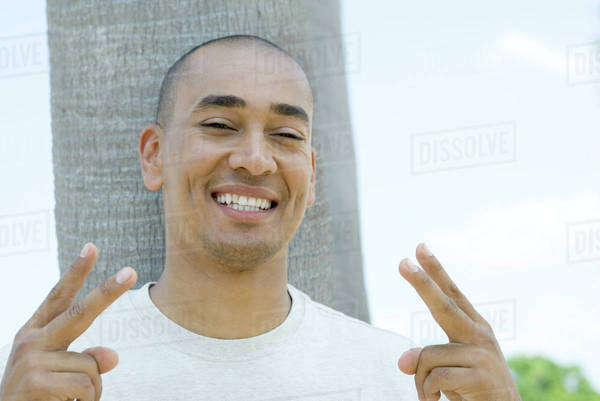 Man giving peace sign and smiling at camera, portrait - Stock Photo ...