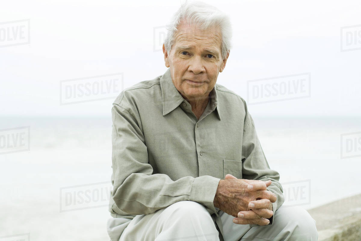 Senior man sitting outdoors, smiling at camera, portrait - Stock Photo ...