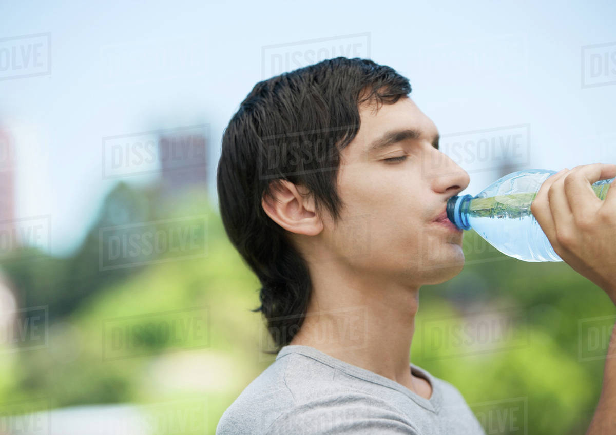 Young man drinking water from bottle - Royalty-free Stock Photo | Dissolve