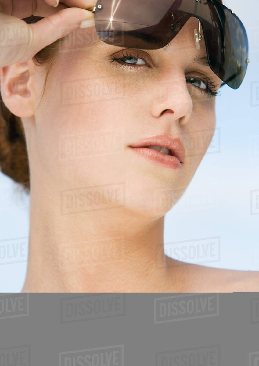 Woman lifting sunglasses - Royalty-free Stock Photo | Dissolve