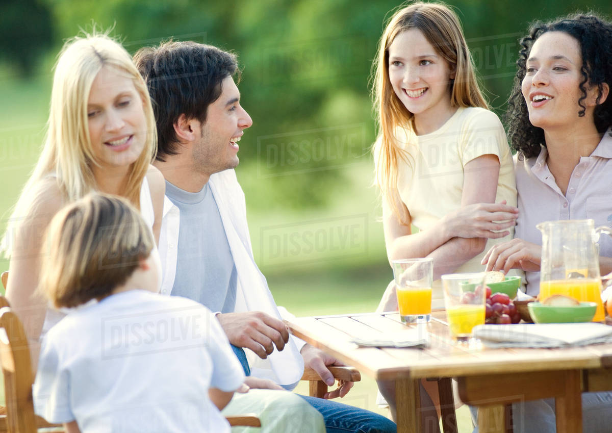 Family and kids sitting around table outdoors - Royalty-free Stock ...