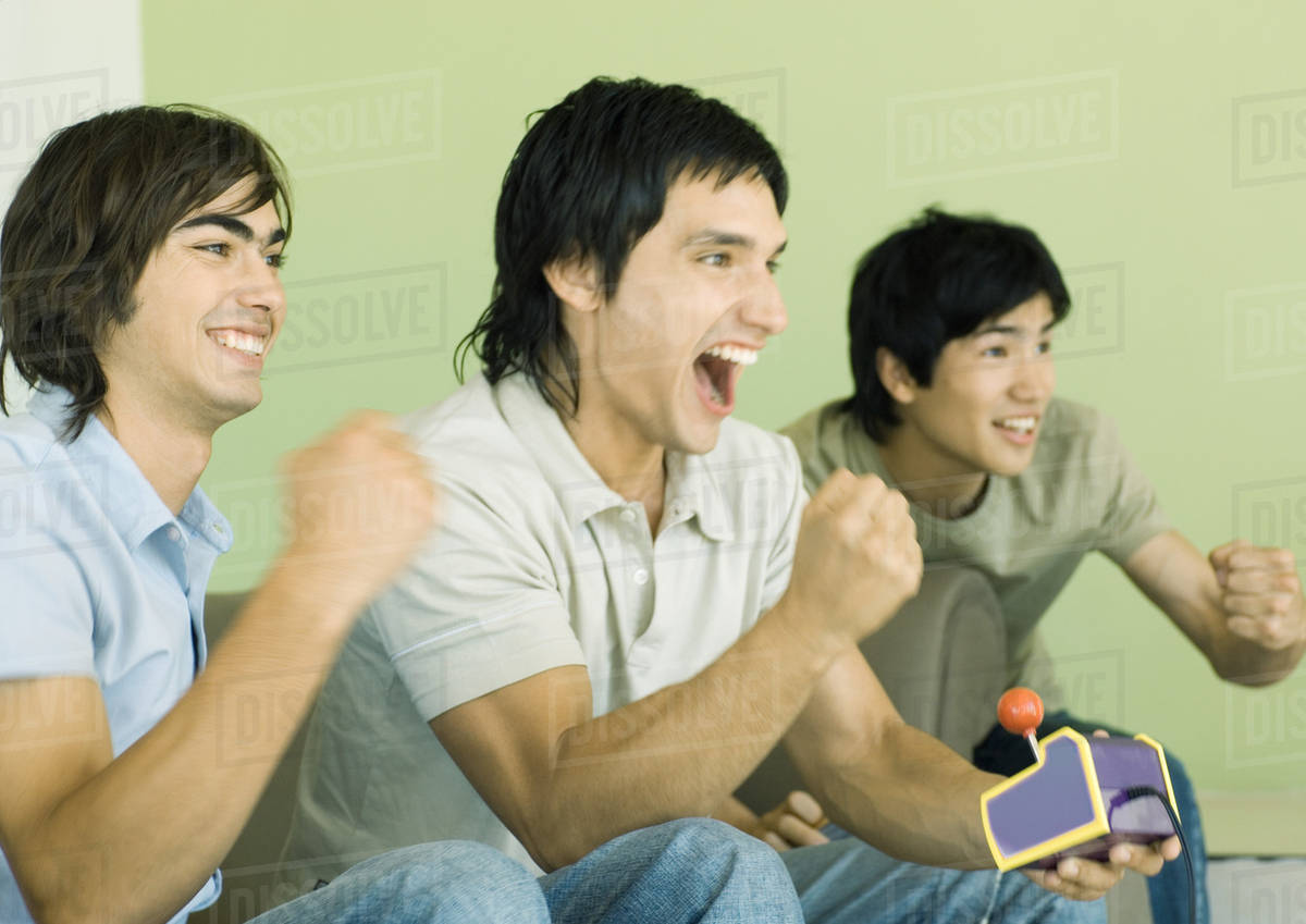 Three young men playing video games - Royalty-free Stock Photo | Dissolve