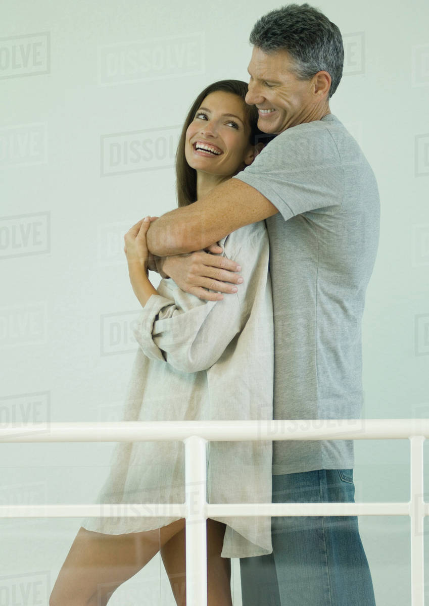Couple Smiling At Each Other Man Standing Behind Woman With Arms