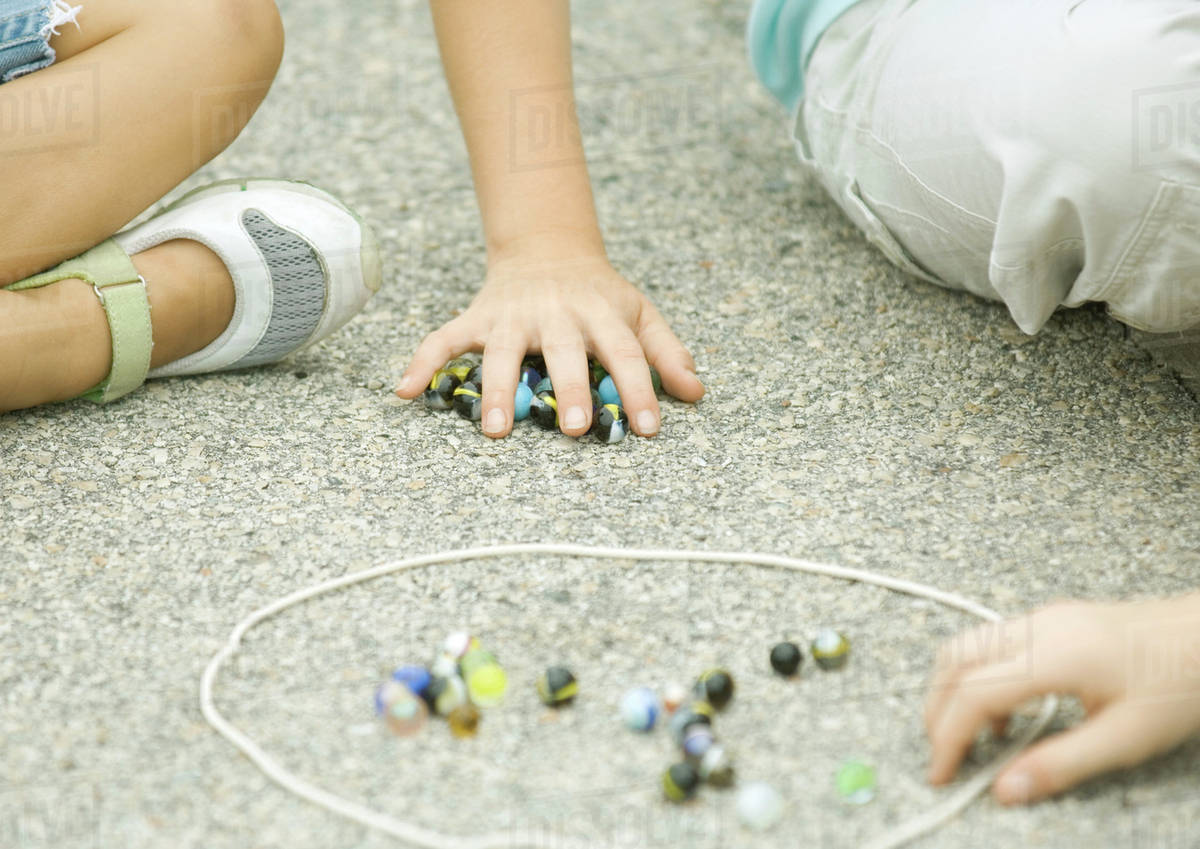 Children playing marbles on asphalt - Royalty-free Stock Photo | Dissolve