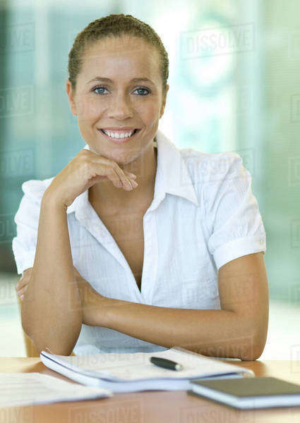 Businesswoman sitting at desk, smiling at camera, portrait - Royalty ...