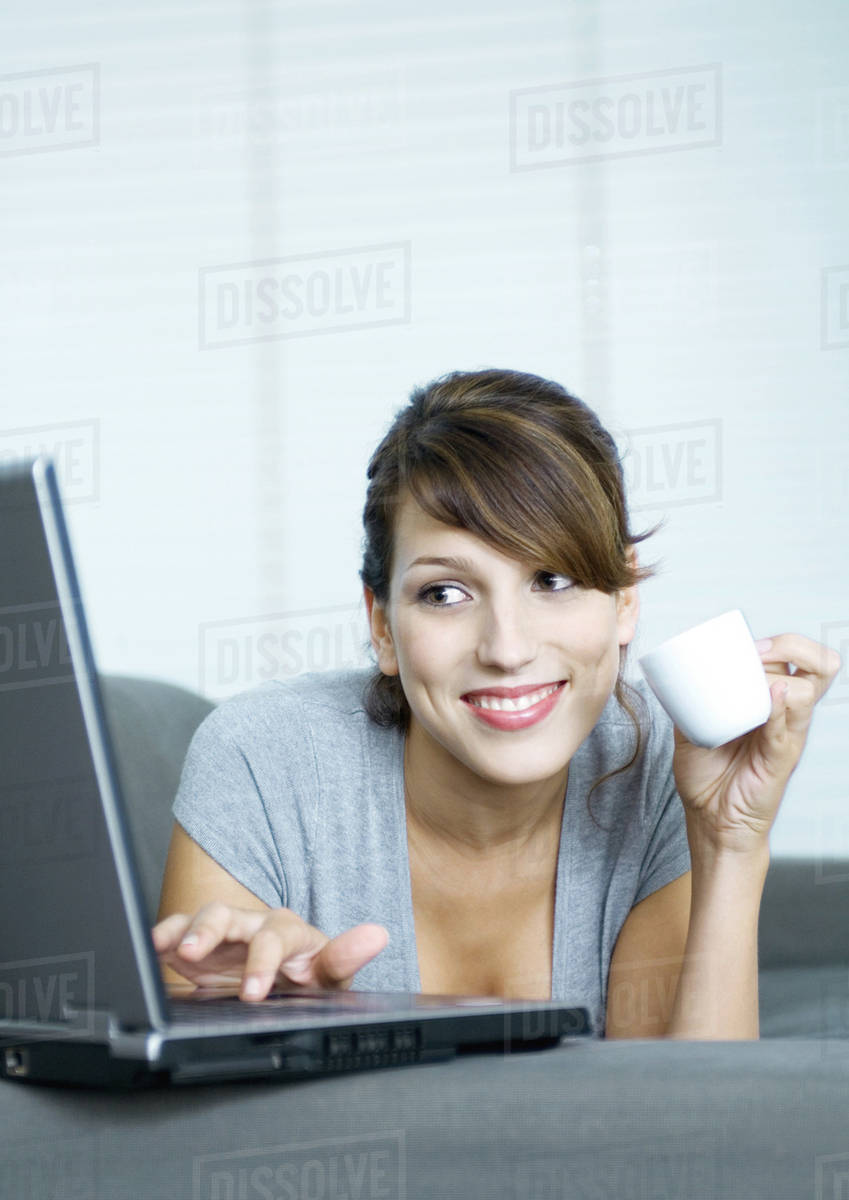 Woman drinking coffee and using laptop - Stock Photo - Dissolve