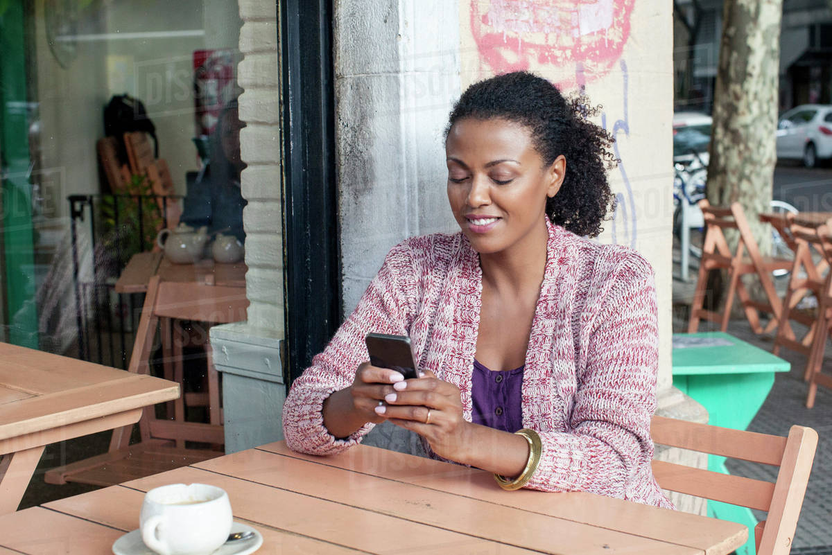 Woman using cell phone at sidewalk cafe - Stock Photo - Dissolve