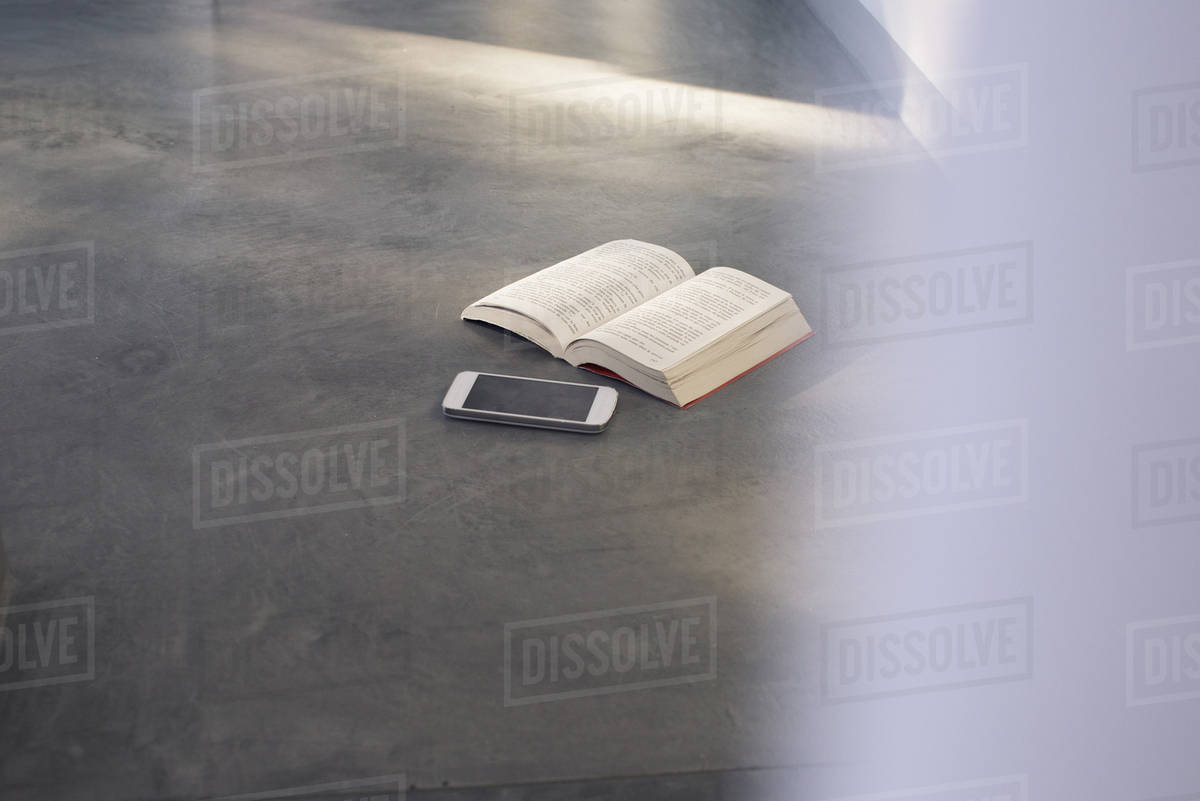 Smartphone and open book lying on floor - Royalty-free Stock Photo ...