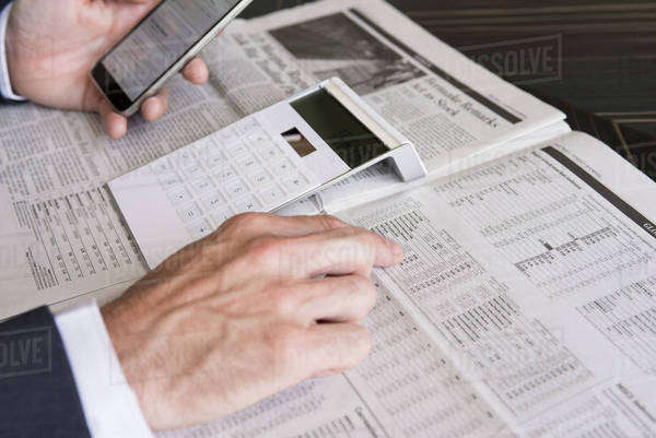 Checking stock market performance using smartphone and newspaper ...