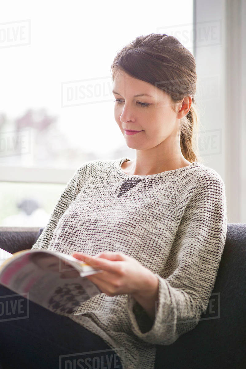 Woman reading magazine at home - Royalty-free Stock Photo | Dissolve