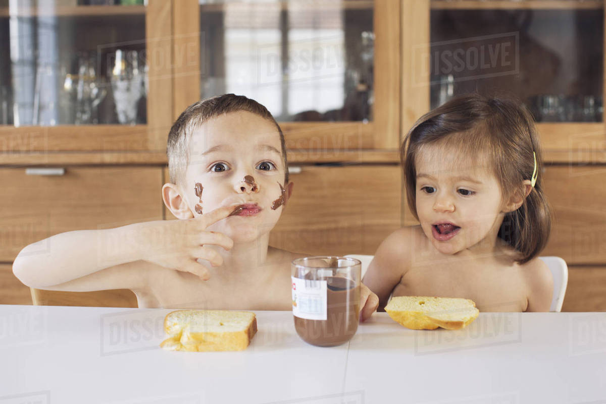 Siblings enjoying chocolate spread and toast for snacks - Royalty-free ...