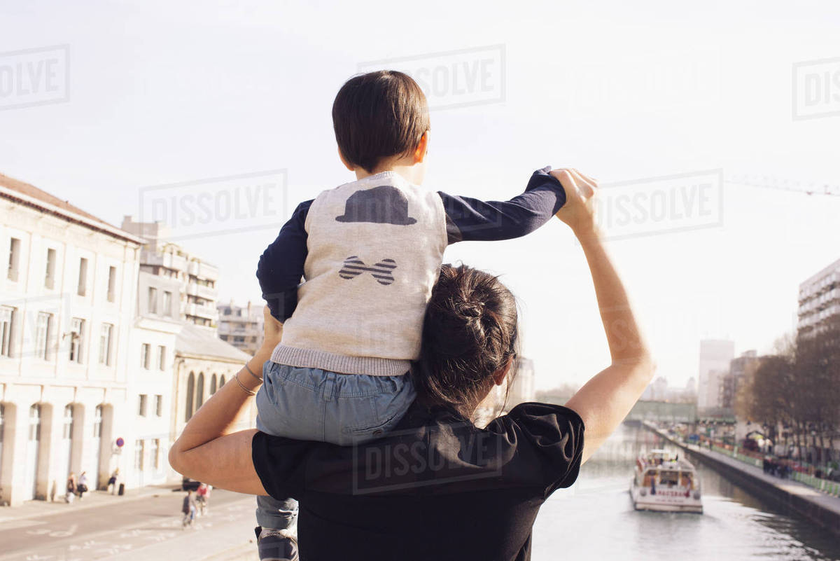 Mother carrying little boy on shoulder, looking at view together ...