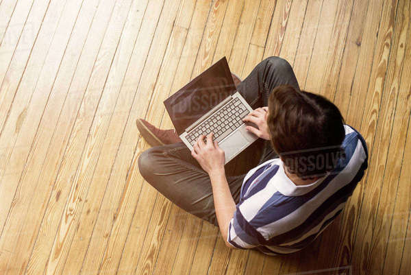 Man sitting indian style on floor using laptop computer - Royalty-free ...