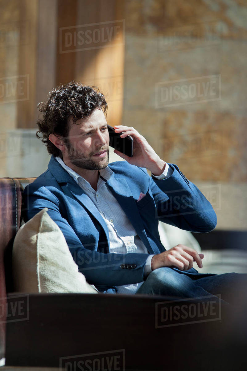 Man talking on smartphone in lobby - Royalty-free Stock Photo | Dissolve