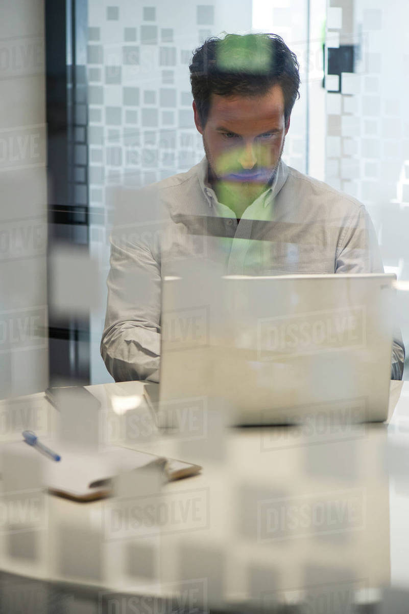Man using laptop computer in office - Royalty-free Stock Photo | Dissolve