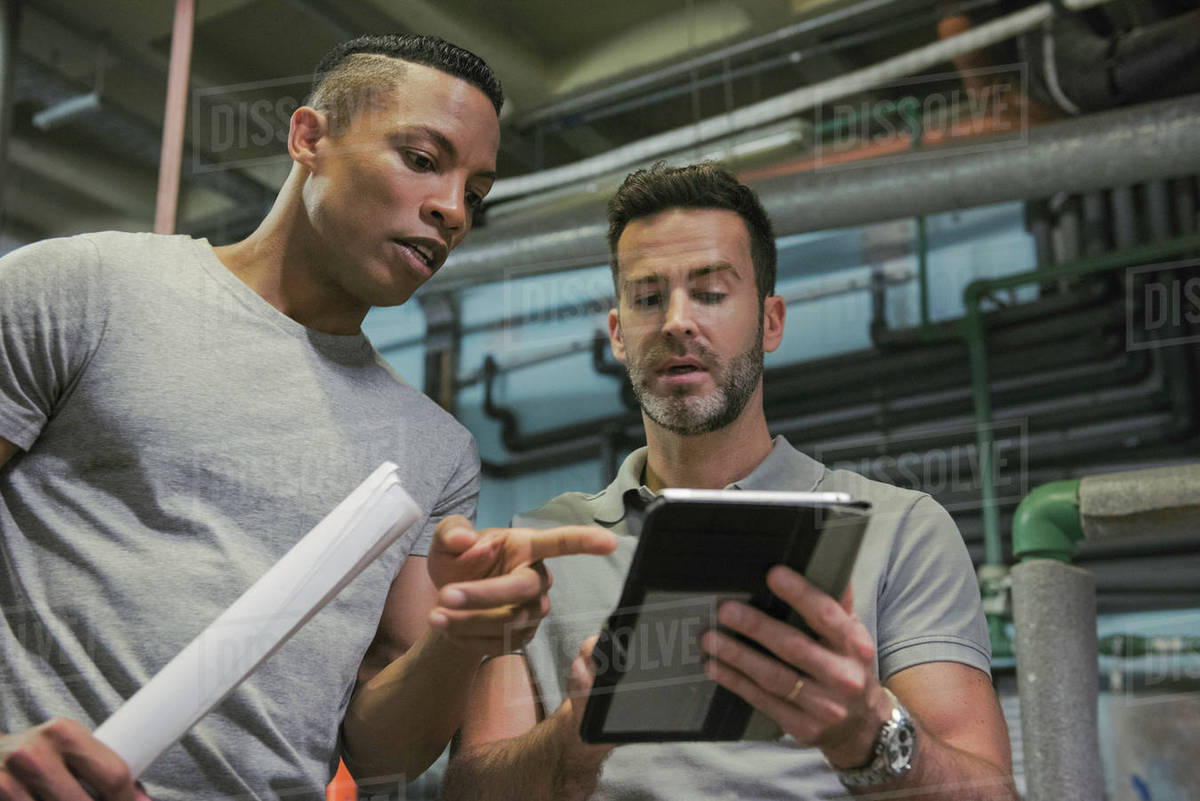 Men working in industrial setting using digital tablet - Royalty-free ...