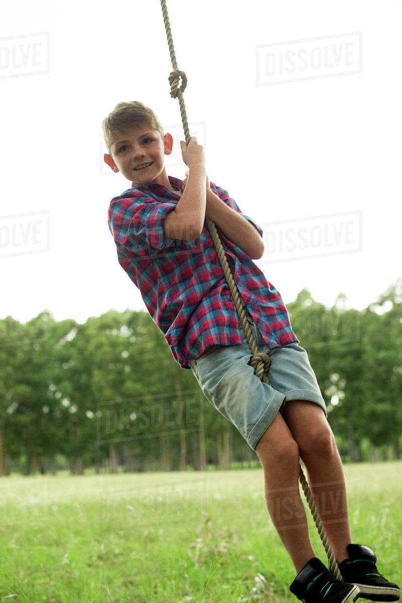 Boy swinging on rope outdoors - Royalty-free Stock Photo | Dissolve
