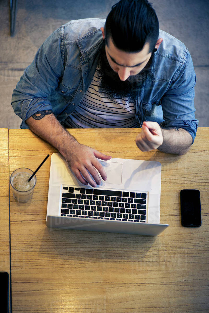 Man using laptop computer in cafe - Royalty-free Stock Photo | Dissolve
