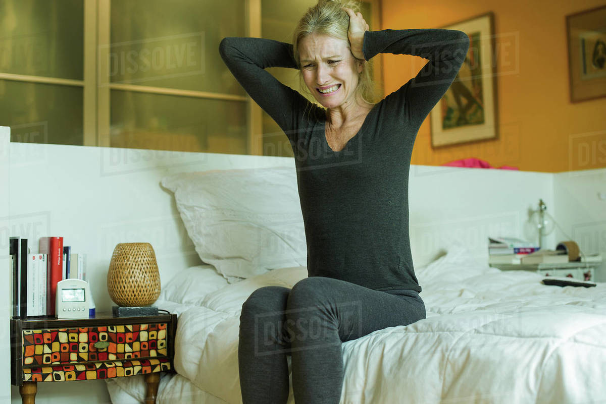 Mature woman holding hands on head in anquish - Stock Photo - Dissolve