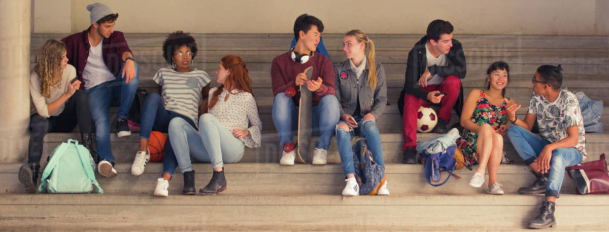 College students hanging out and chatting together on bleachers ...
