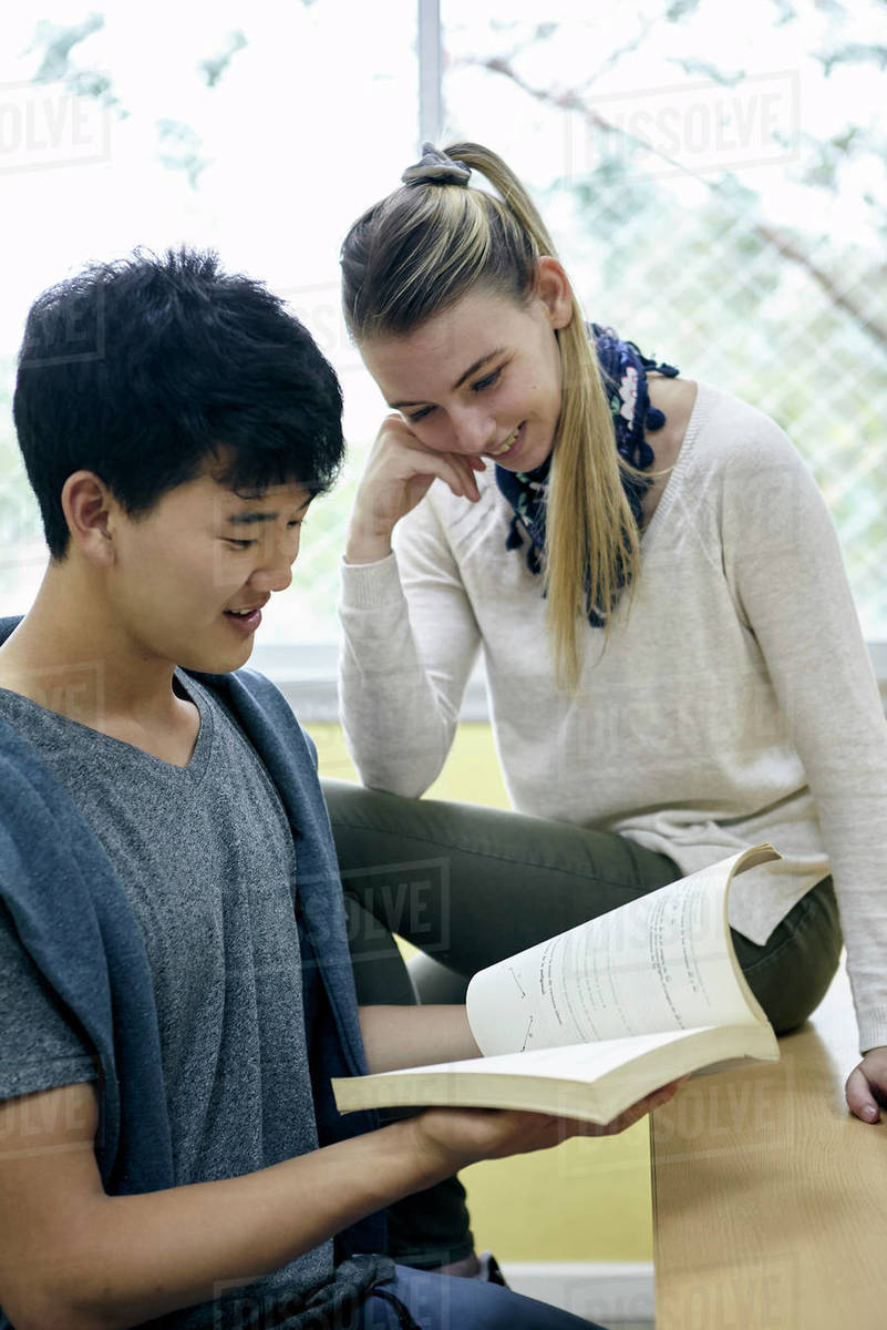 Students looking at textbook together - Royalty-free Stock Photo | Dissolve