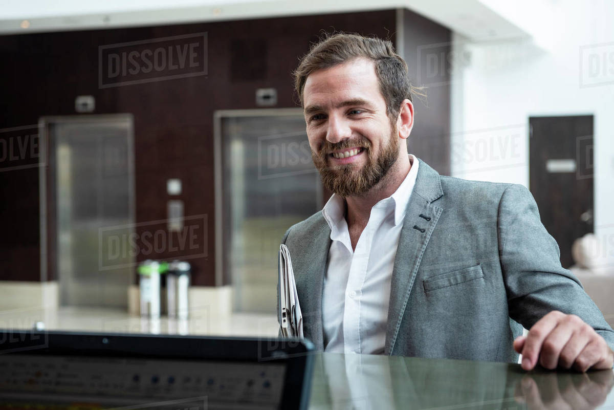 Businessman standing at hotel reception counter - Royalty-free Stock ...