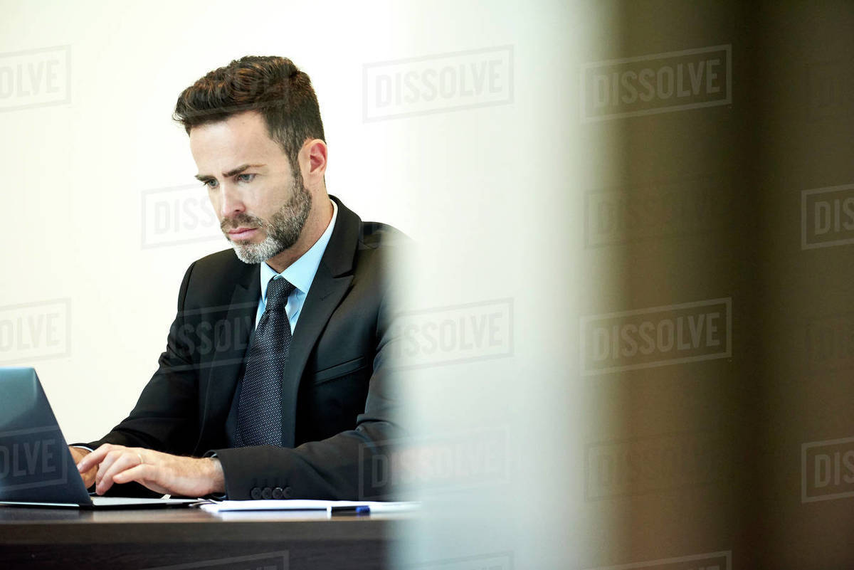Businessman using laptop in office - Stock Photo - Dissolve