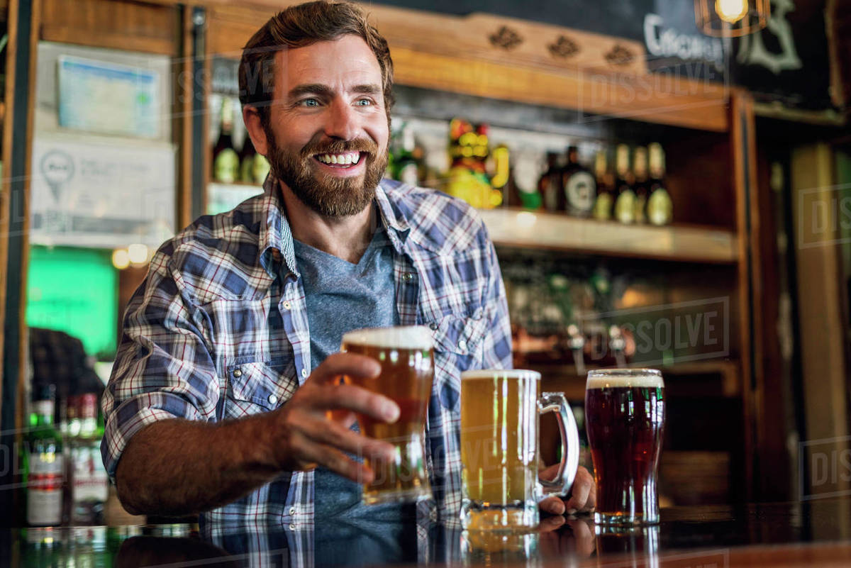 Smiling man serving beer - Royalty-free Stock Photo | Dissolve
