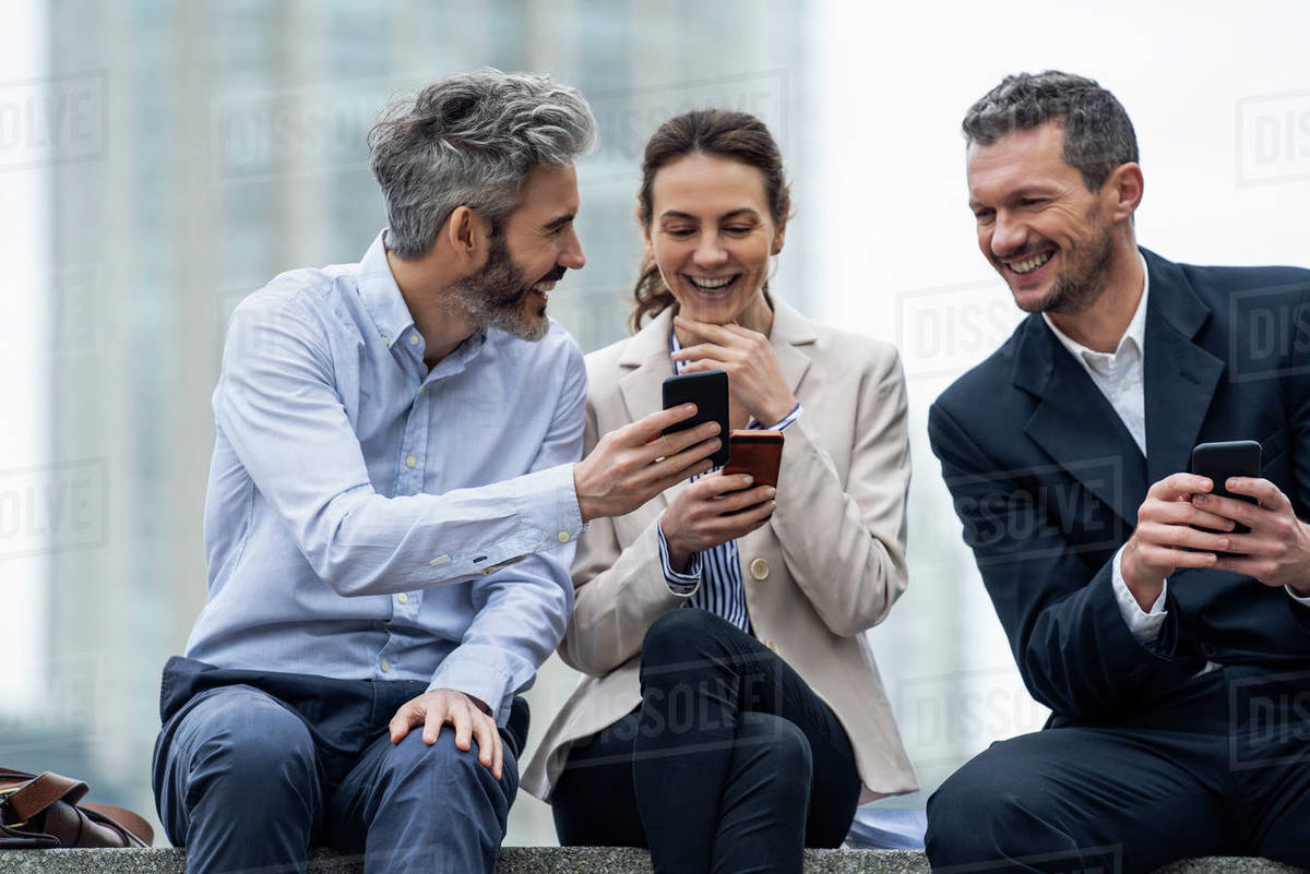 Business people using smartphones in public park - Royalty-free Stock ...