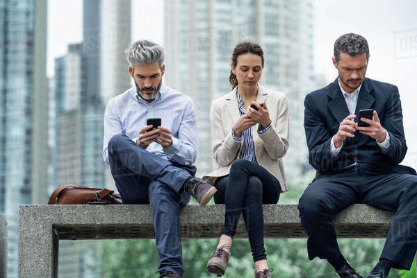 Business people using smartphones in public park - Stock Photo - Dissolve