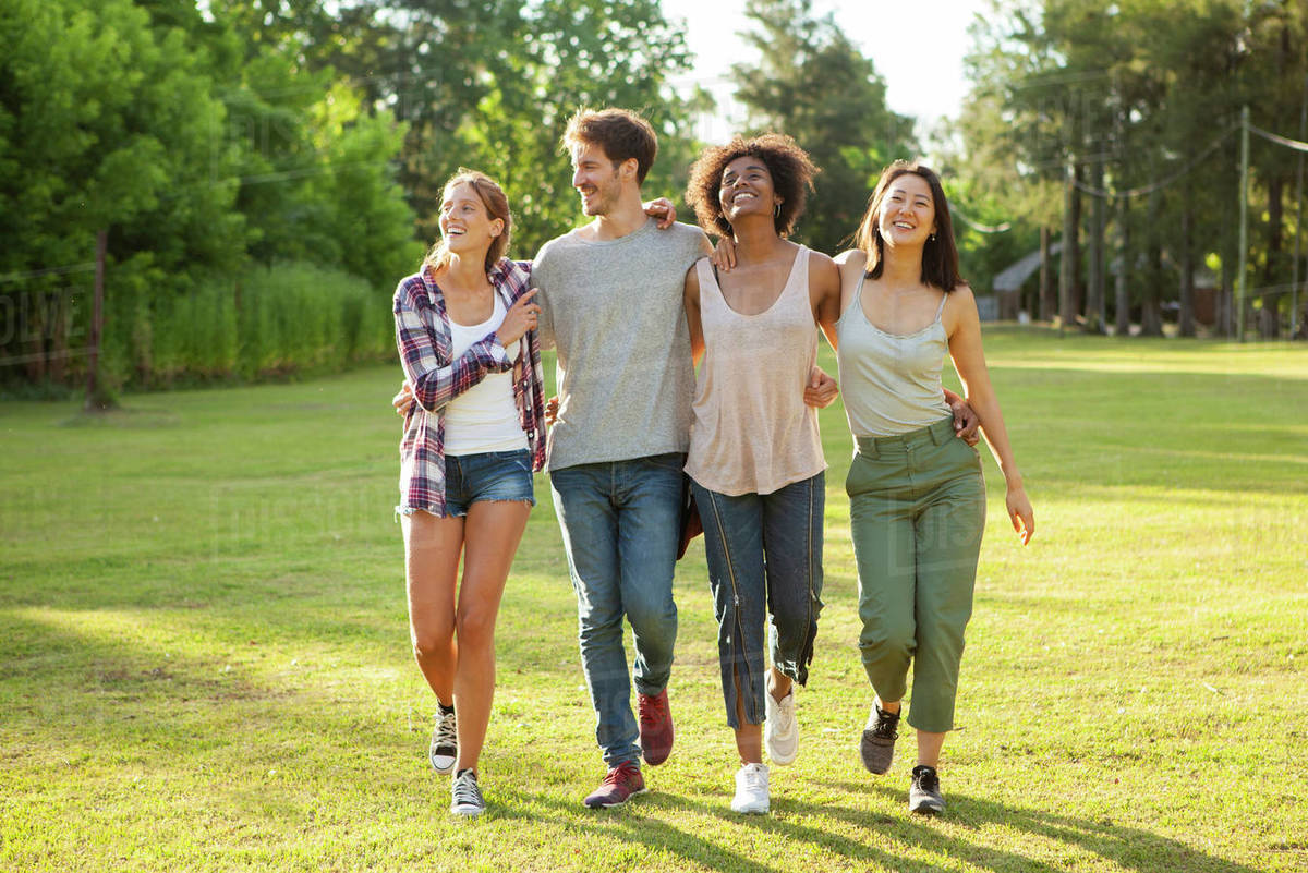 Happy young friends walking together in park - Royalty-free Stock Photo ...