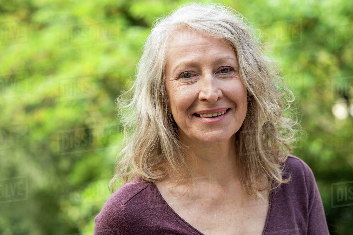 Portrait of middle-aged lady looking at camera while sitting outdoors ...
