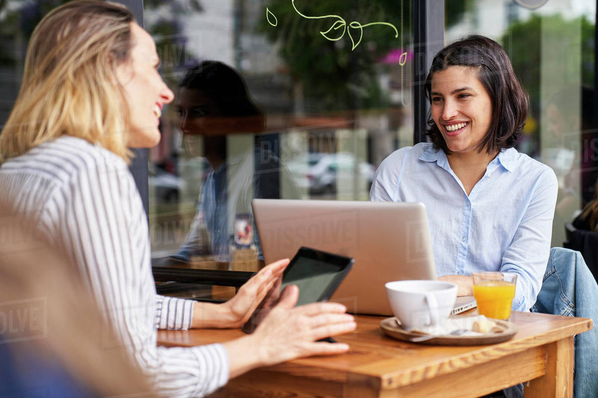 Mid-shot of two smiling female co-workers enjoying their work in ...