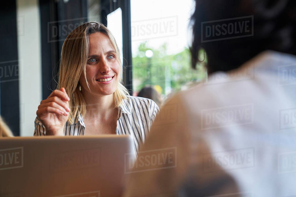 Mid-shot of two female co-workers discussing work matters at company's ...