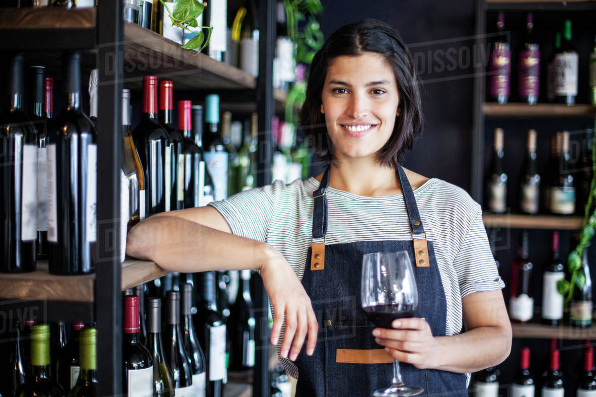 Female sommelier holding glass of wine while looking at the camera ...
