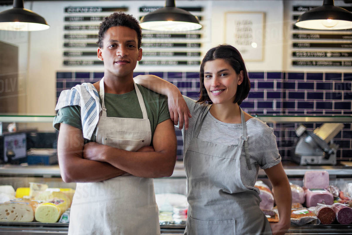 Confident grocery store owners looking at the camera while standing ...