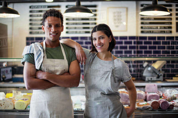 Cheerful grocery store owners standing in front of refrigerator ...