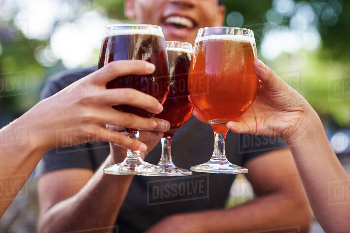 Mid-shot of three glasses of beer being raised in a toast - Royalty ...