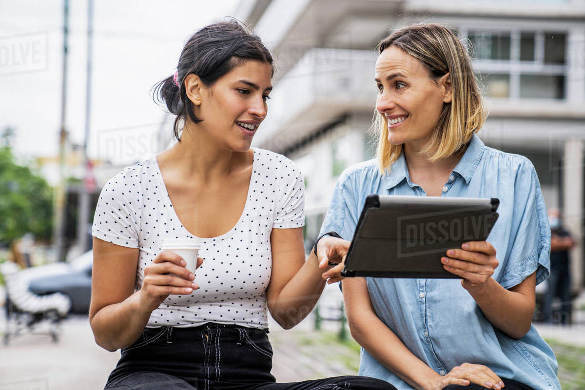 Front view mid-shot of two female co-workers talking about work matters ...