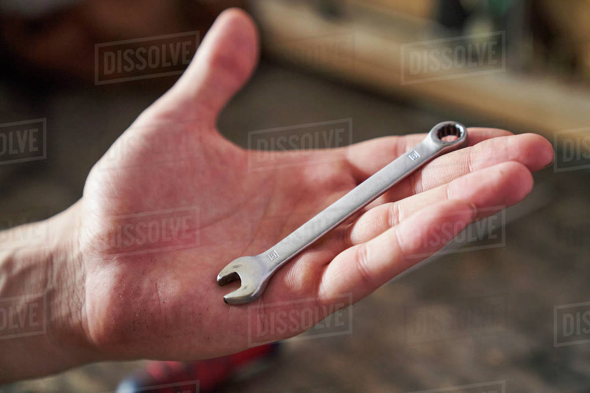 Close-up shot of combination spanner on the palm of a person's hand ...