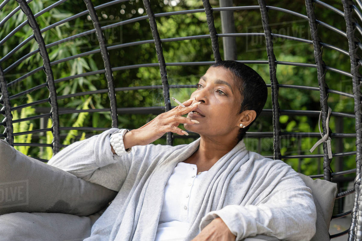 Mature woman smoking and looking away - Royalty-free Stock Photo | Dissolve