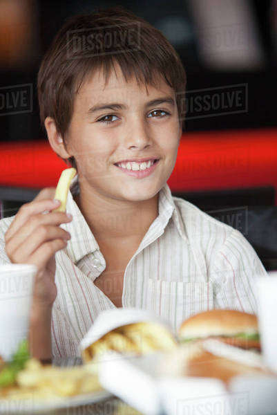 Boy eating fast food, portrait - Royalty-free Stock Photo | Dissolve