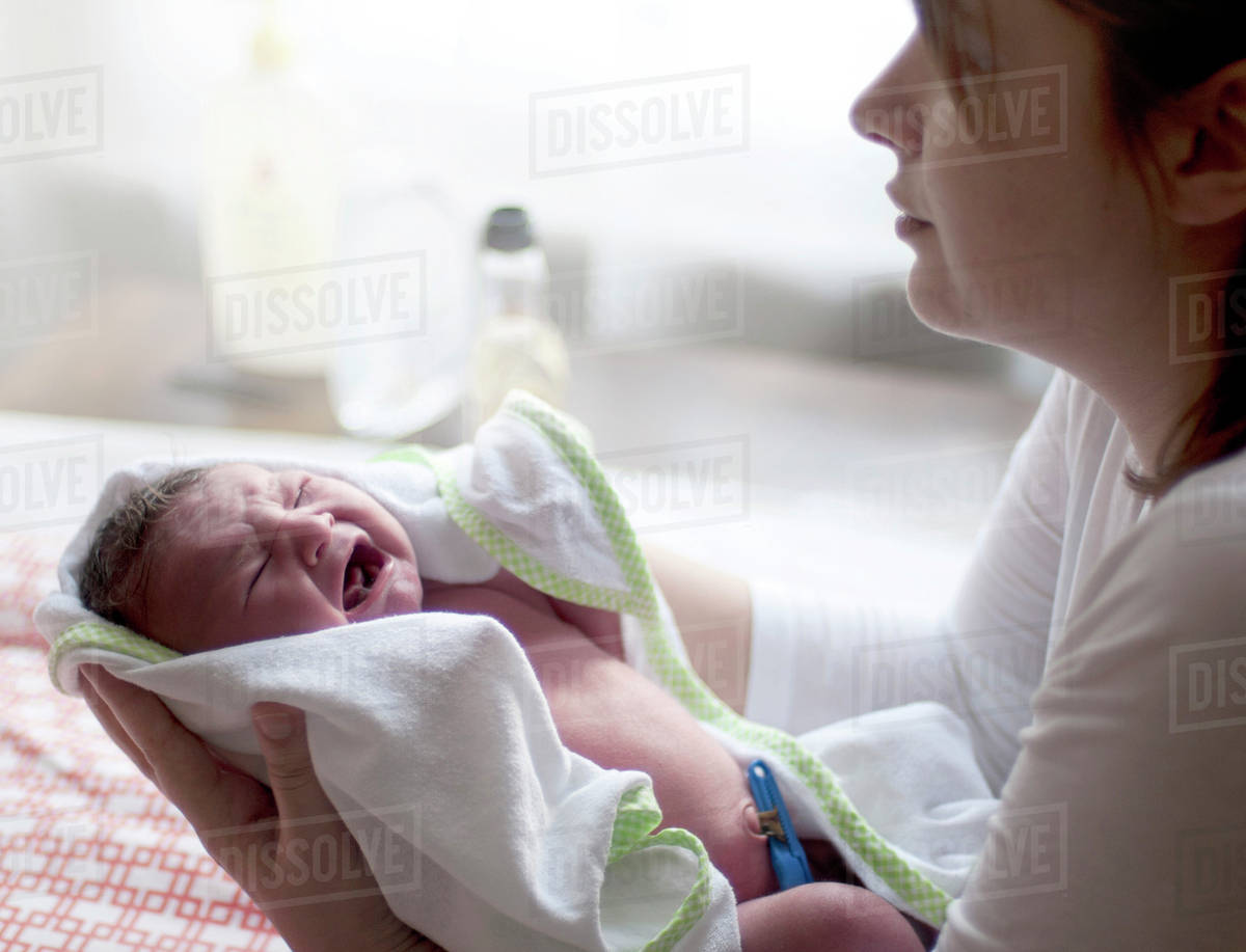 Woman holding crying new born baby - Stock Photo - Dissolve