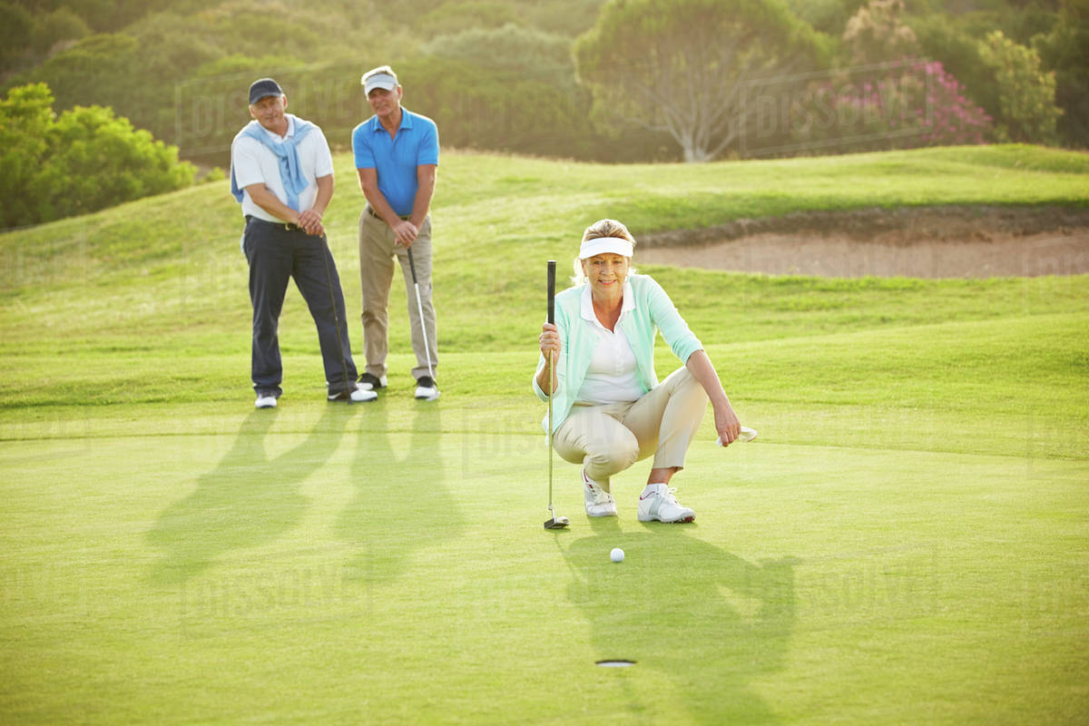 Senior friends playing golf on course - Stock Photo - Dissolve