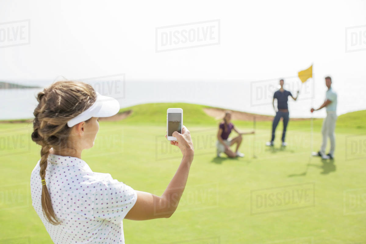 Woman photographing friends on golf course - Royalty-free Stock Photo ...